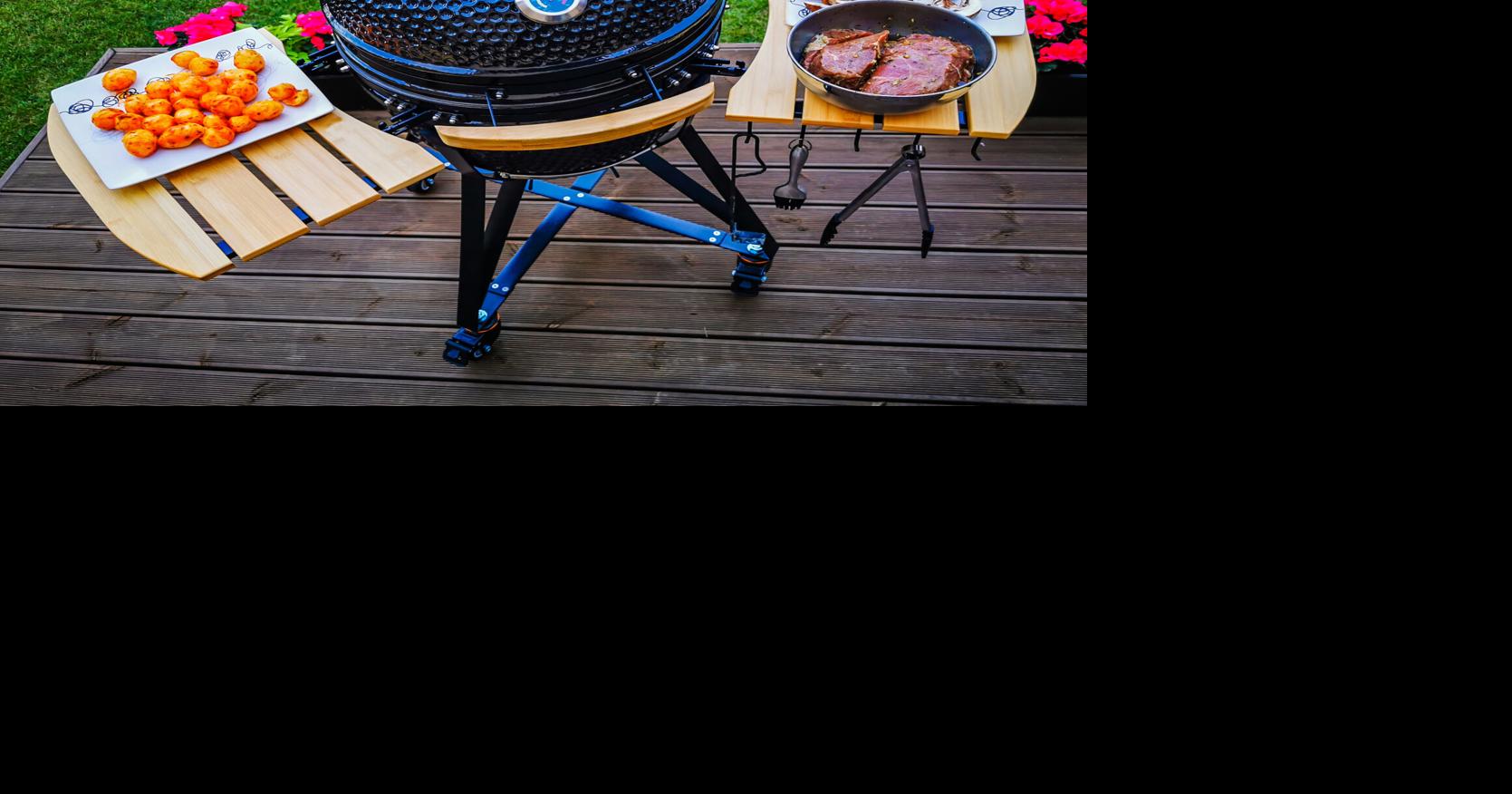 Large kamado type barbeque grill with beef steaks and vegetables ready ...