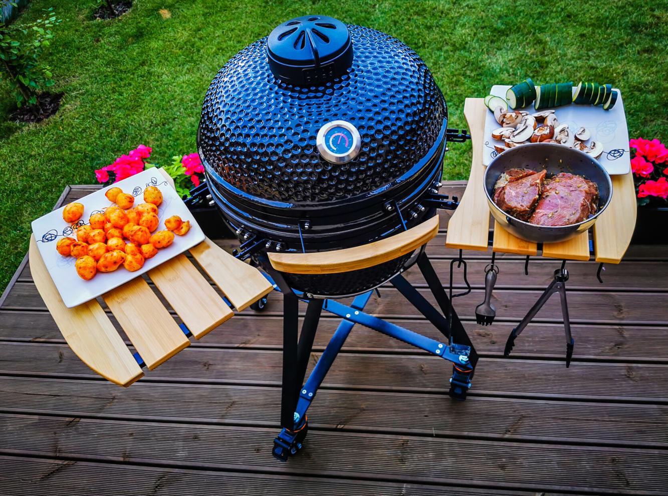 Large kamado type barbeque grill with beef steaks and vegetables ready ...