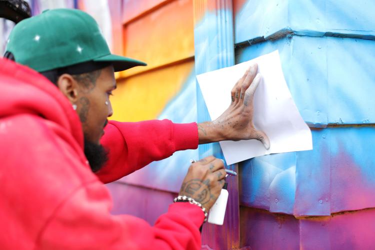 Photos: Artist Maleek Adams paints a mural covering the building at ...