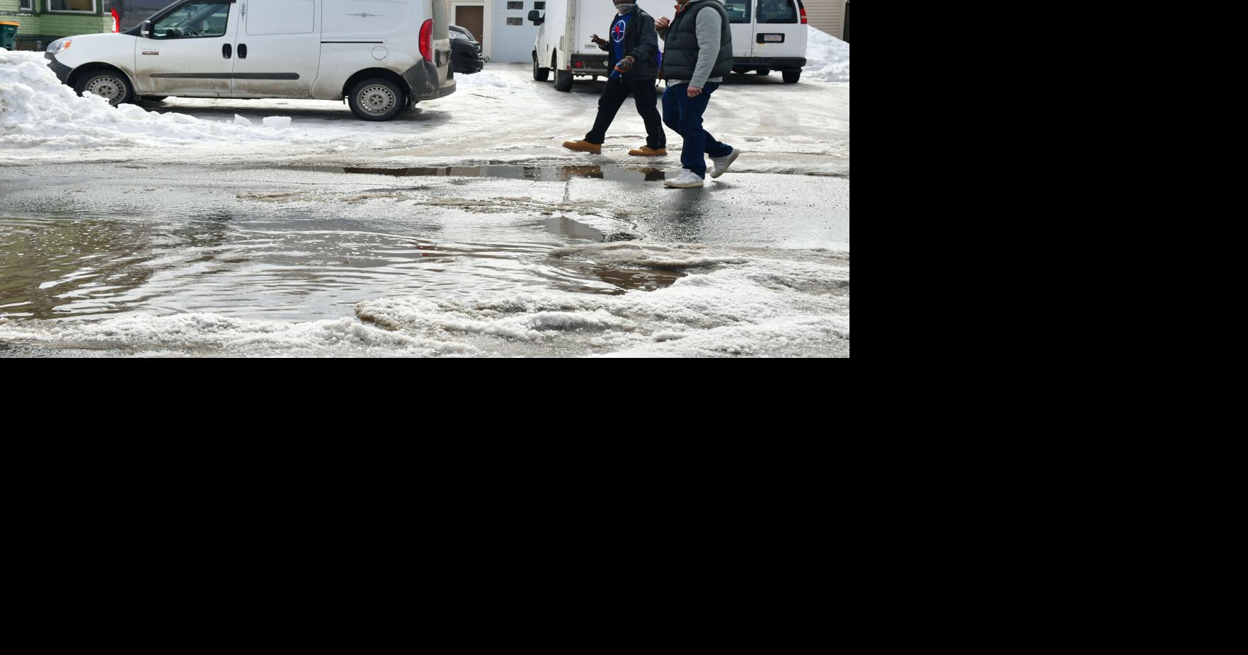 Two people walk on a street with puddles and ice | | berkshireeagle.com