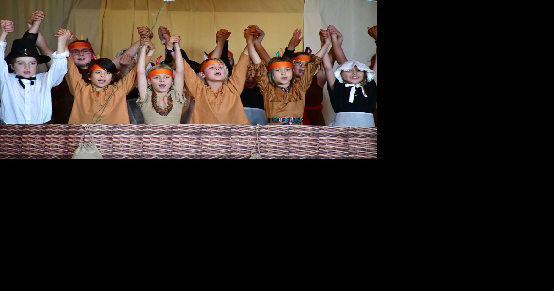Children dressed as pilgrims and indians hold up their arms and sing ...