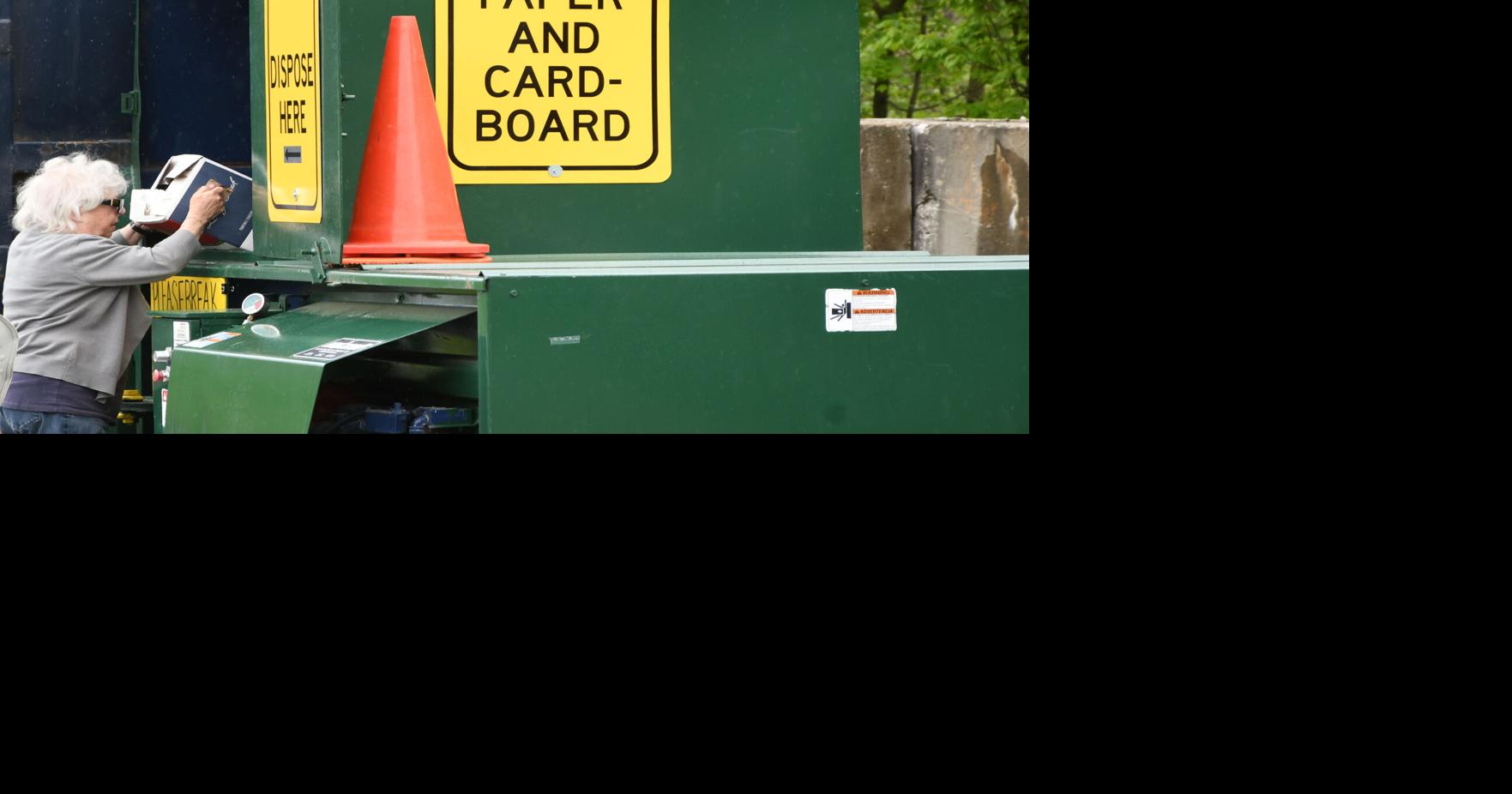 A woman puts her cardboard and paper into a compactor ...