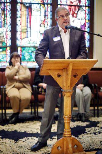 Peter Marchetti speaking at podium in front of stained glass window ...