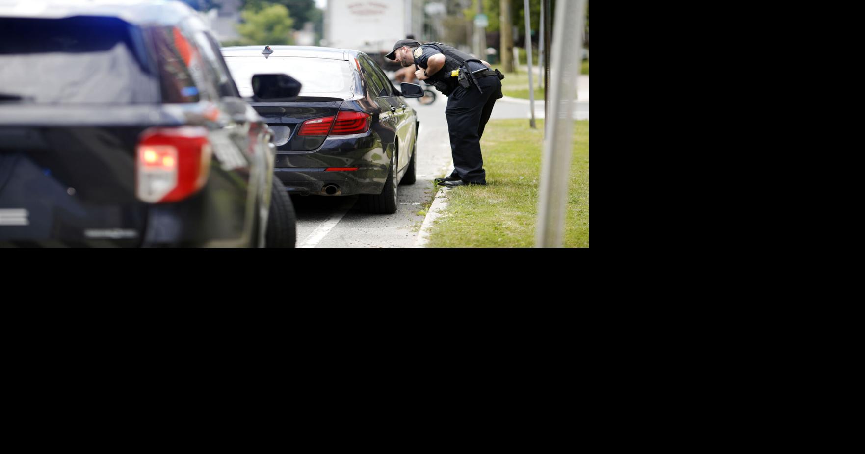 police officer bending over to look inside pulled over car ...