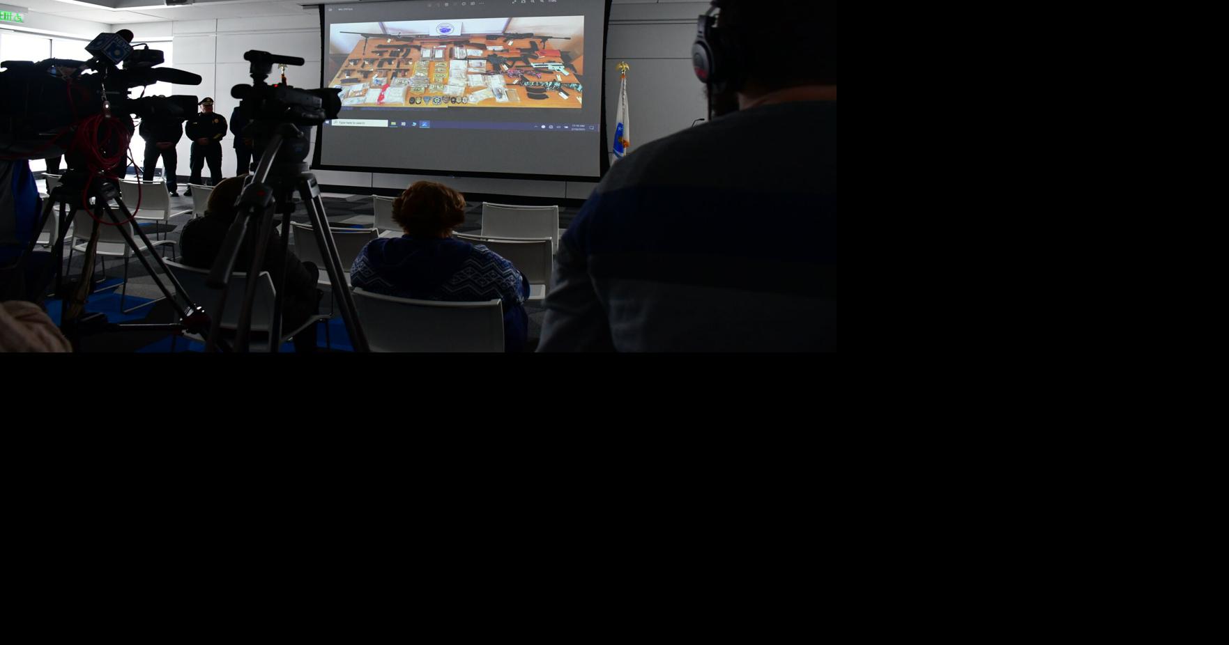 A press conference shows media and an image on a screen of the seized ...