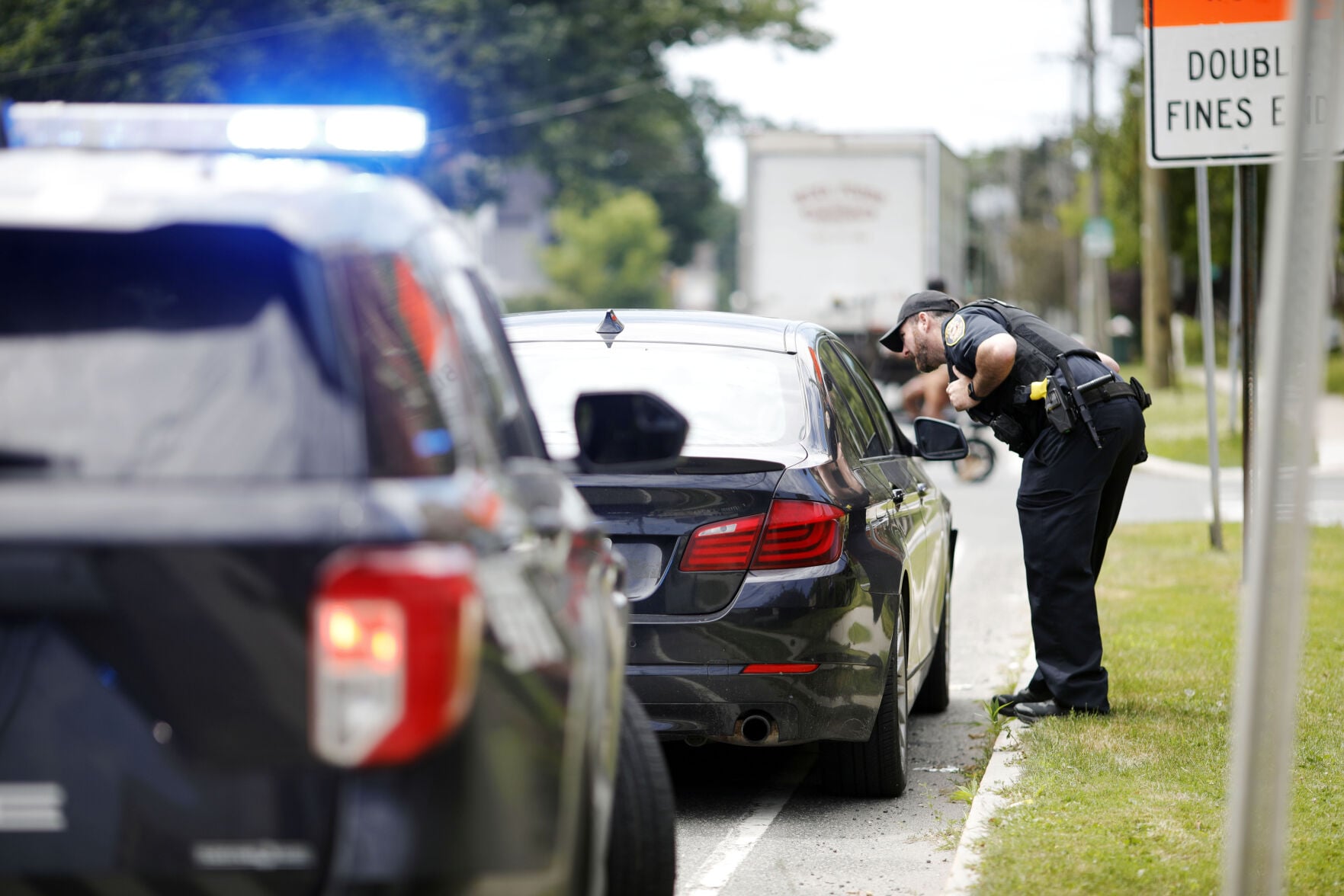 police officer bending over to look inside pulled over car | | The ...