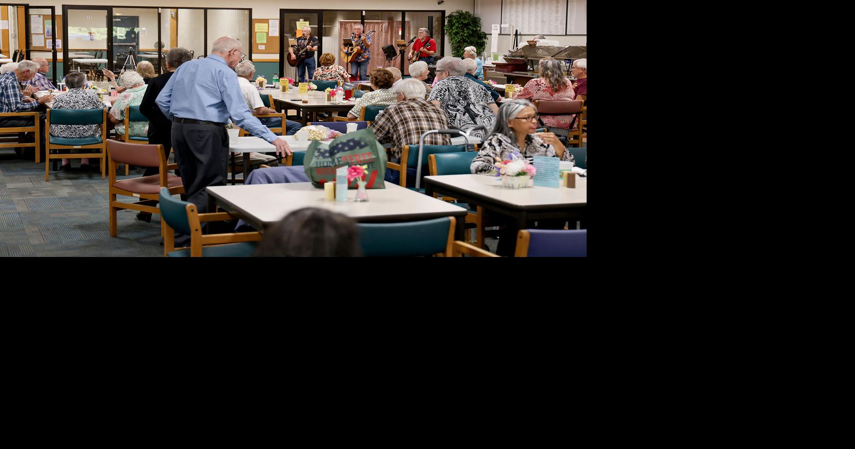 Residents gather to enjoy a meal and listen to a performance by The ...