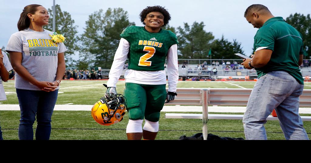 Nathaniel Peat smiles up at the stands accompanied by his parents on ...