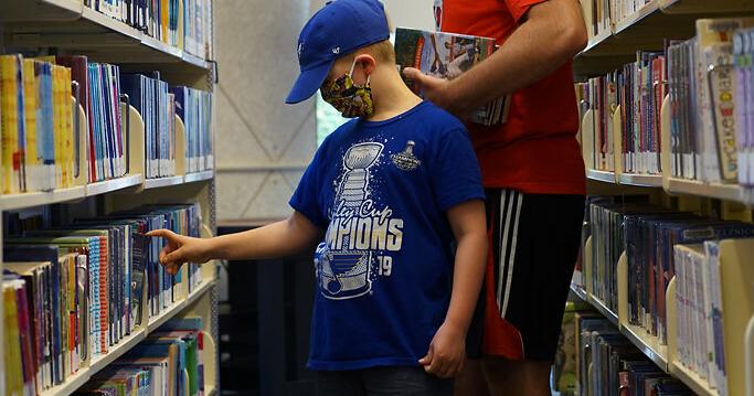 Jeff Moorman and his son, Jensen, look for books Wednesday at the ...