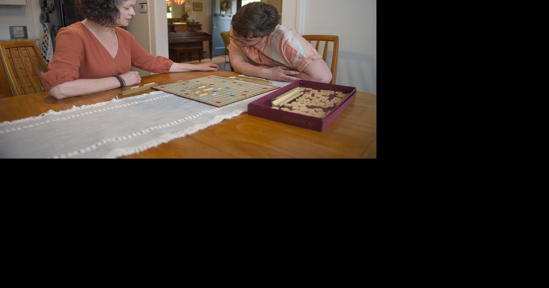 Meg Ross, left, and her son Parker Ross put tiles on a Scrabble board ...