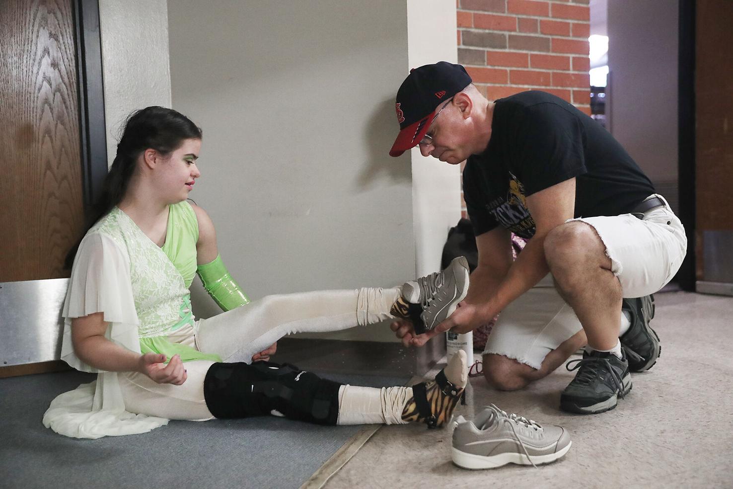 Christian Basi helps Julianna Basi put on her foot and ankle braces ...
