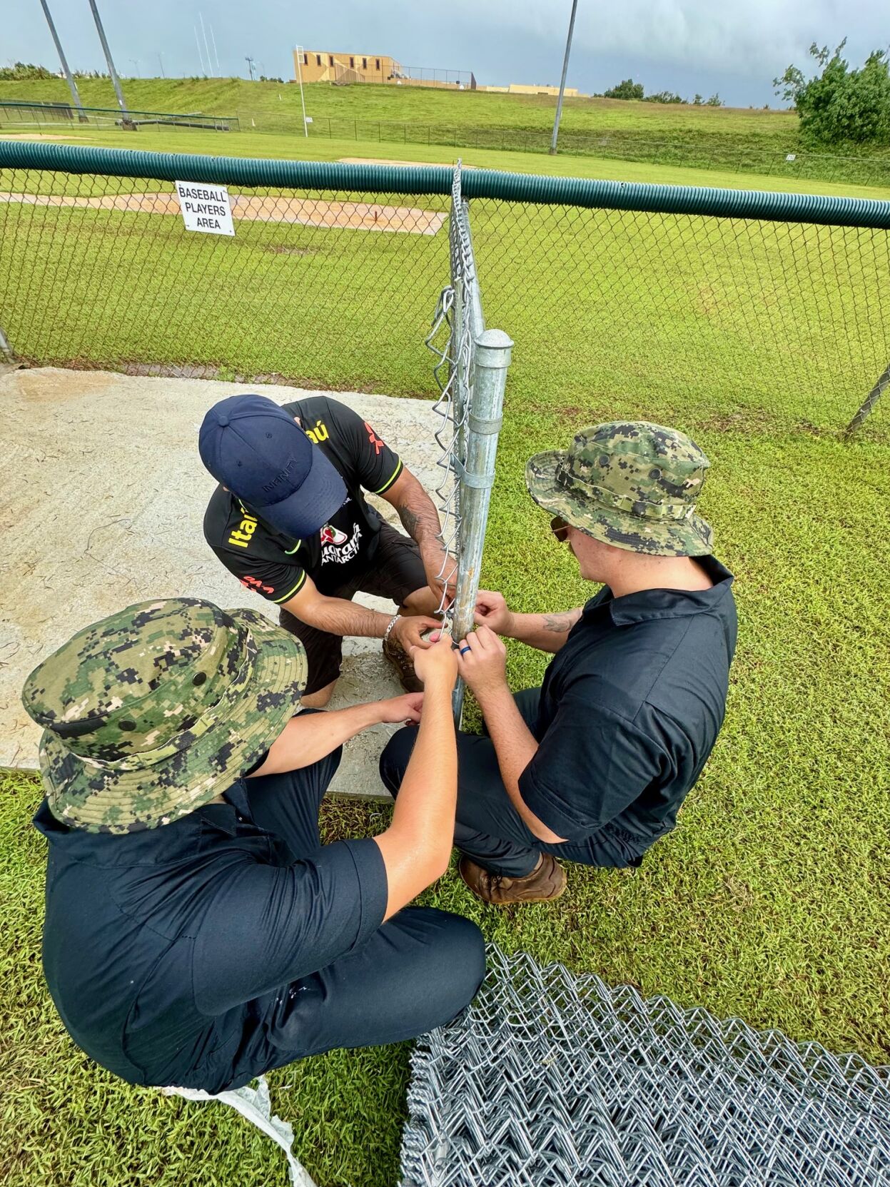 Navy Seabees install new fencing material at Okkodo High School baseball, softball fields ...