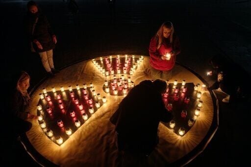 People light candles set in shape of a radiation sign in front of a ...