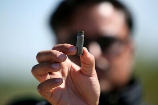 A man holds up a bullet casing found at the Mexican football field ...