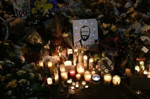 A drawing of Alex Pretti is displayed alongside candles at a makeshift ...