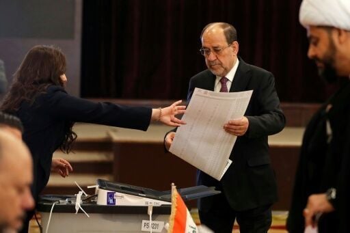 Former Iraqi prime minister Nouri al-Maliki holds the ballot paper at a ...