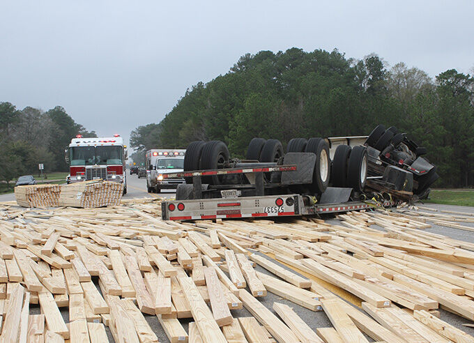 Truck overturns spilling a large load of lumber across the highway ...