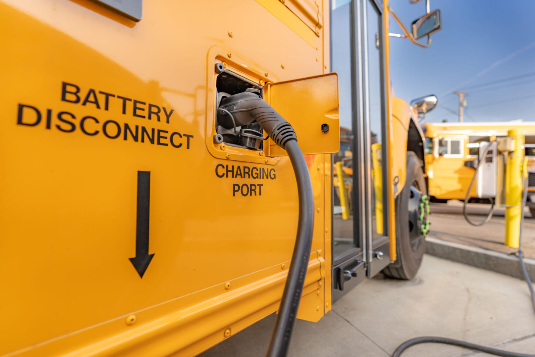 Yellow electric school bus plugged in at a charging station ...