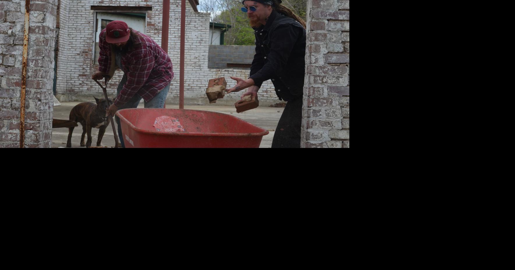 Jerry Shaver and Christian Griffith shovel bricks while being filmed by ...